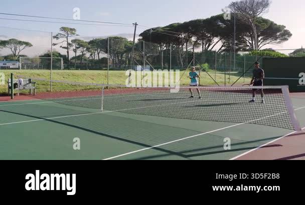 Tossing tennis ball, Asian woman and male partner trading shots ...