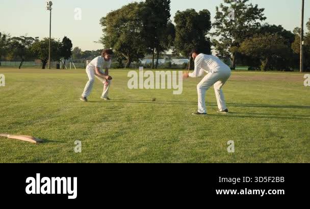 Practicing underarm bowling, diverse male duo repeating pickup-return ...