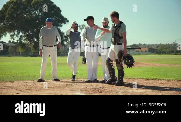 Diverse male teammates high-fiving celebrating and walking off baseball ...