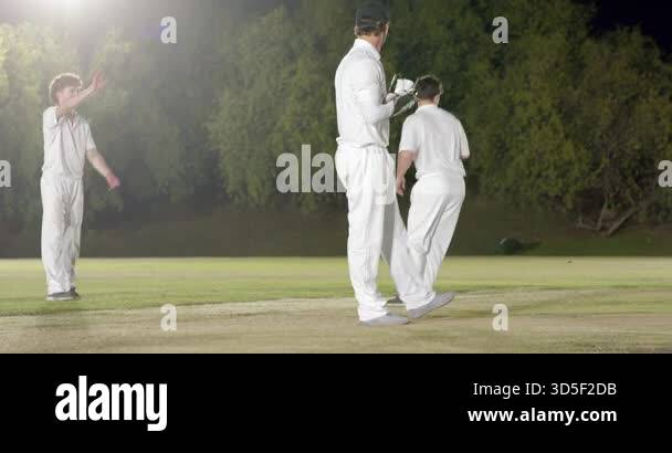 Crouching wicket-keeper catching ball after bowler run-up signalling ...