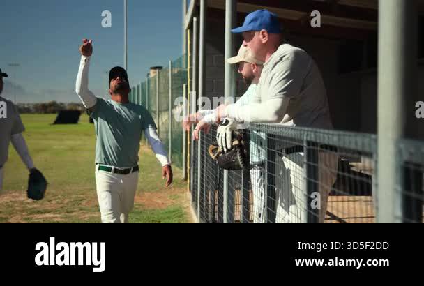 Walking African American player tossing baseball by dugout, starting ...