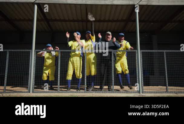 Spotting catch, diverse male teammates and coach leaning over railing ...