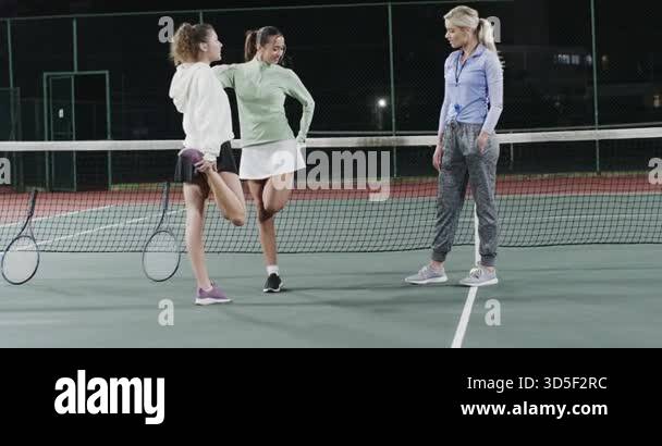 After picking up ball-feeding stick, female coach and players warming ...