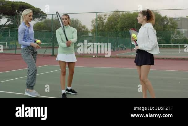 Showing grip, adjusting stance and swing, diverse female coach training ...