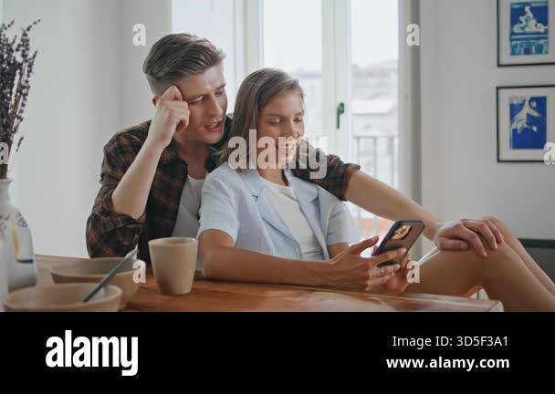 Smiling couple using cellphone indoors. Sweethearts enjoying moment ...
