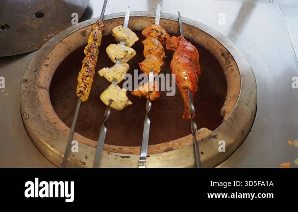 Marinated chicken and seekh kebab sizzling inside traditional clay ...