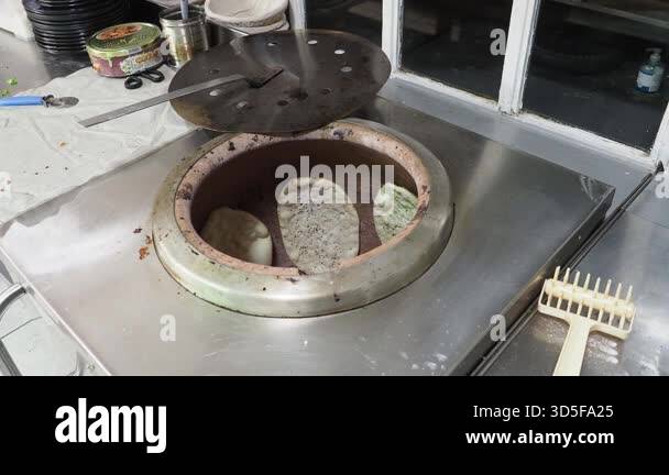 Professional chef baking various types of naan bread in a traditional ...