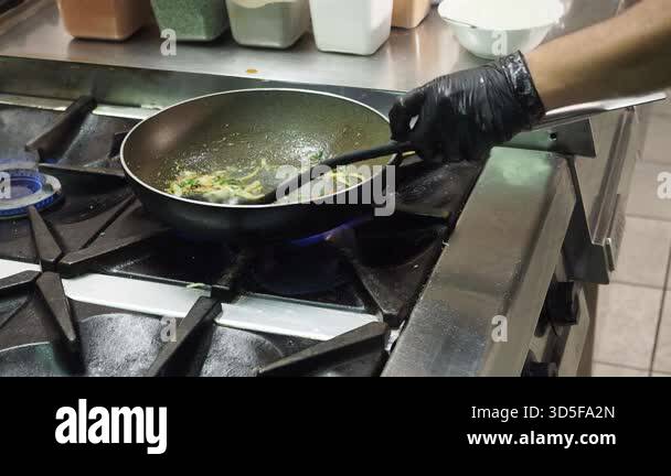Skilled chef preparing fresh vegetables in commercial kitchen, sauteing ...