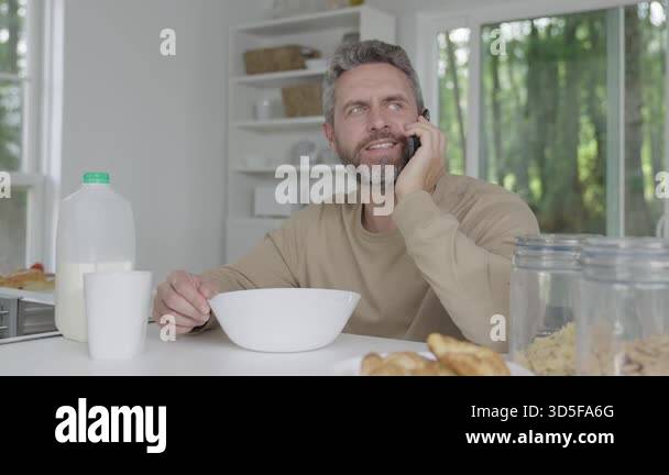 Hispanic guy eating breakfast while managing online tasks. Morning home ...