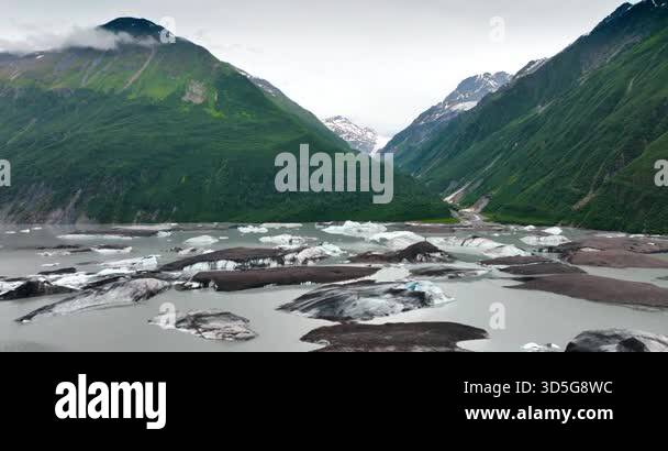 Amazing verdant mountains with a river with melting ice. Snow-capped ...