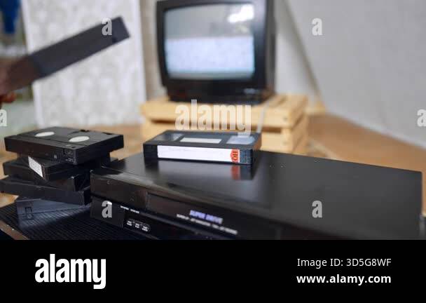 Hand takes a tape from the VHS recorder and puts into the player. Man ...