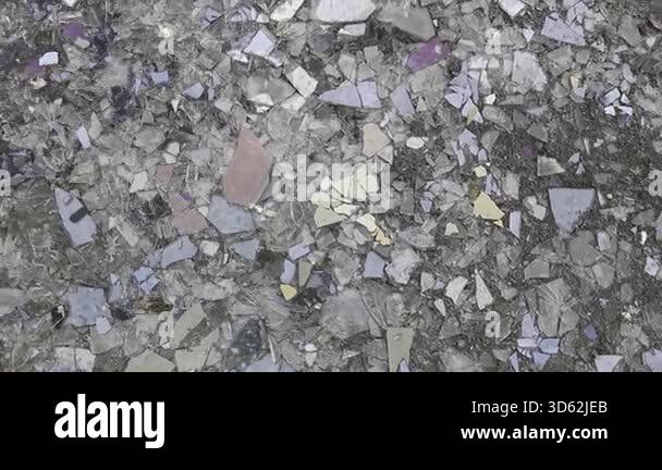 Broken glass shards lie chaotically on ground surface during daytime ...