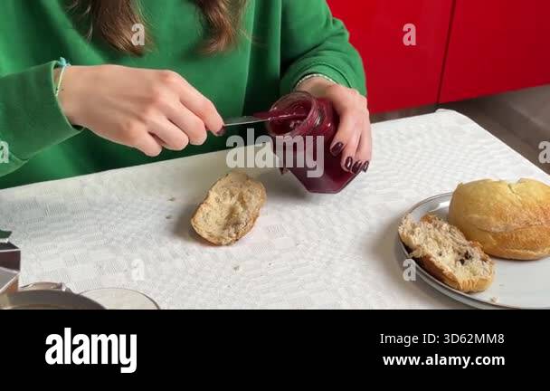 A woman in a green sweater prepares a breakfast routine. She spreads ...