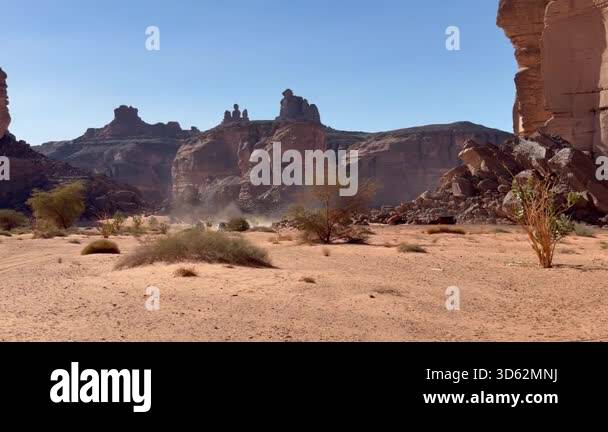 4x4 vehicles traverse the sandy desert floor of the Akakus Mountains in ...