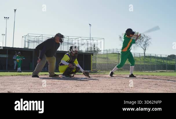 Pitch arriving at home plate triggers male batter swinging and missing ...