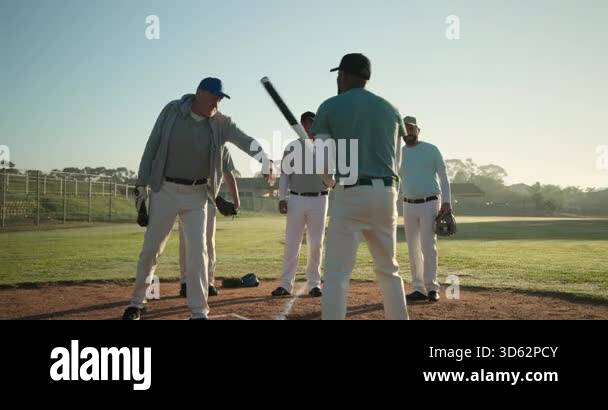 Senior coach tapping bat guiding teenage batter adjusting grip on home ...