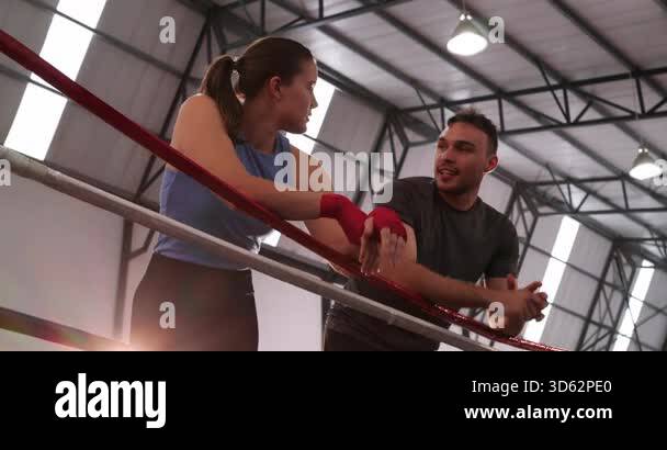 After drill female boxer leaning on ropes and coach demonstrating ...