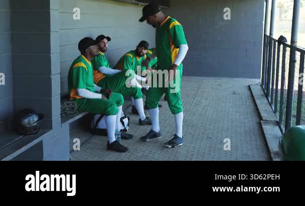 Male baseball player walking into dugout high-fiving teammates showing ...