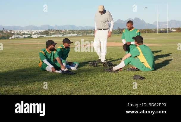 Entering coach greeting diverse teammates sitting on outfield grass ...