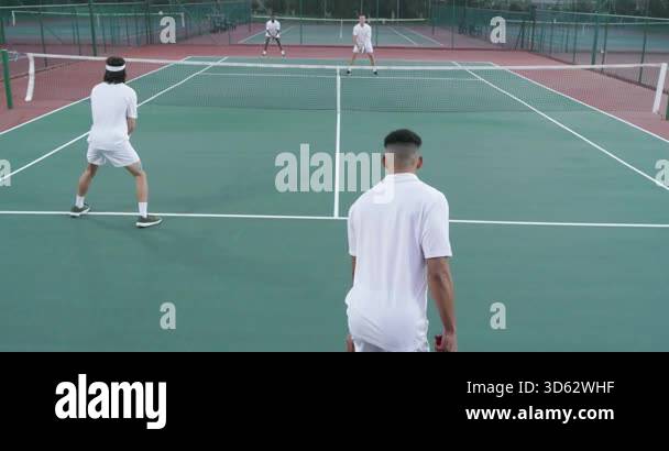 Bouncing ball prompting Adult Asian man serving shot on outdoor court ...