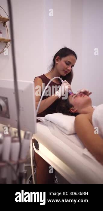 Professional female beautician using modern cosmetology equipment to ...