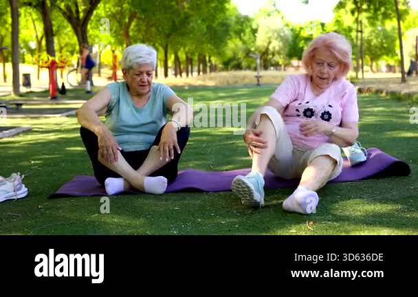 Senior woman experiencing a sudden leg cramp while her friend looks on ...