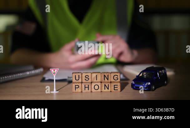 A person in a high-visibility vest focuses on their phone, surrounded ...