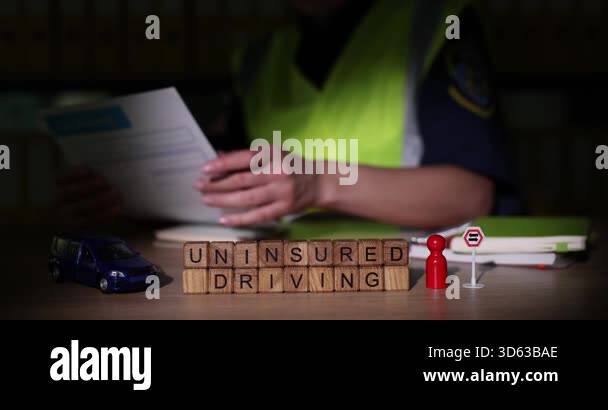A police officer examines documents regarding uninsured driving late at ...