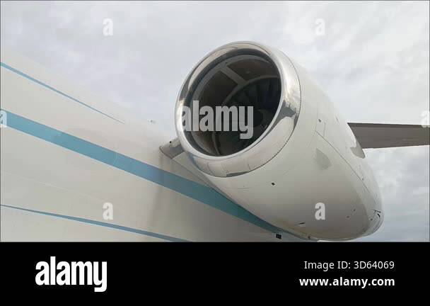 Close-up of a jet engine rotating fan on aircraft fuselage under cloudy ...