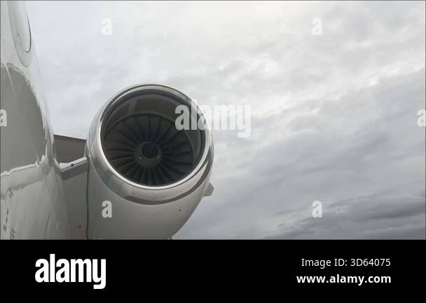 Close-up of a jet engine rotating fan on aircraft fuselage under cloudy ...