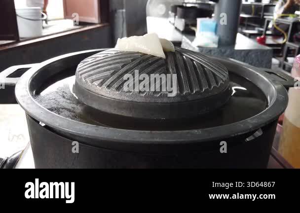 Traditional Thai barbecue grill pan, known as Moo Kratha, with a piece ...