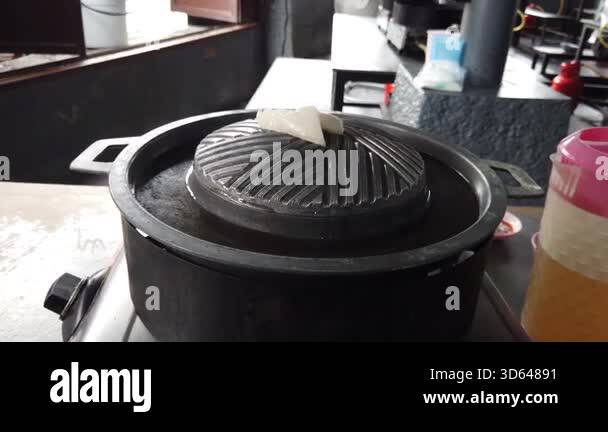 Traditional Thai barbecue grill pan, known as Moo Kratha, with a piece ...
