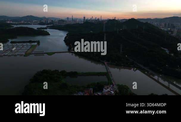 Dark twilight view of a city skyline across flat water and foreground ...