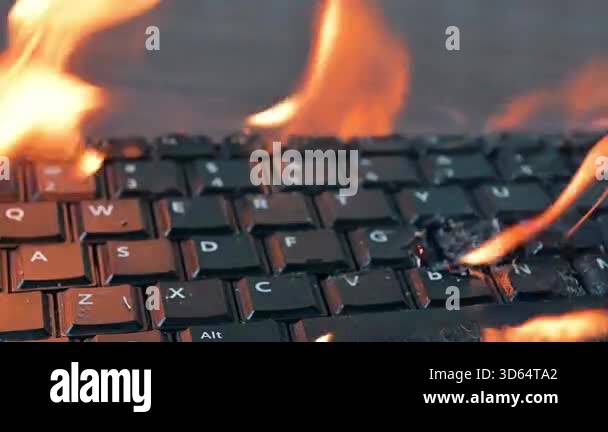 Burning keyboard. Keyboard is engulfed in flames on a desk.Close up of ...