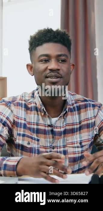 Good-looking smiling friendly 25-aged black-skinned guy sitting in ...