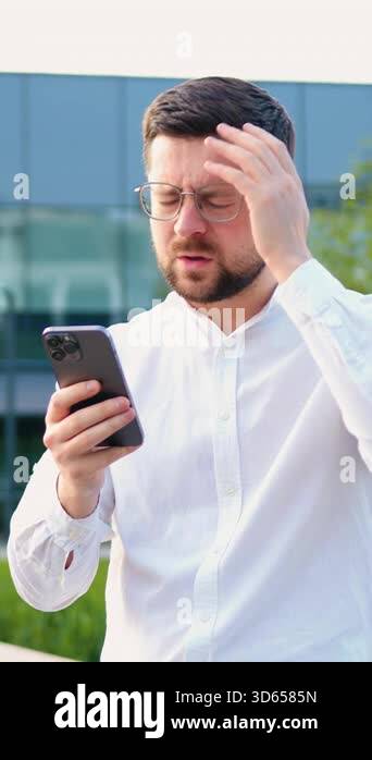 Single sad man in white shirt checking mobile phone walking in city at ...