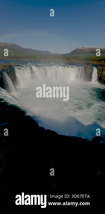 Godafoss waterfall flows powerfully through rugged terrain in Iceland ...