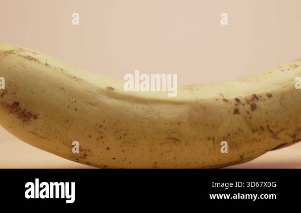 A ripe banana slowly rotates in a smooth macro close-up, showing ...