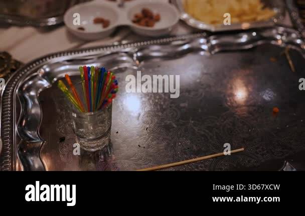 A collection of colorful skewers remains on a silver platter after an ...