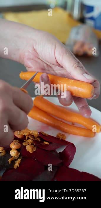 closeup of hand peeling carrots for salad preparation, detailed view of ...