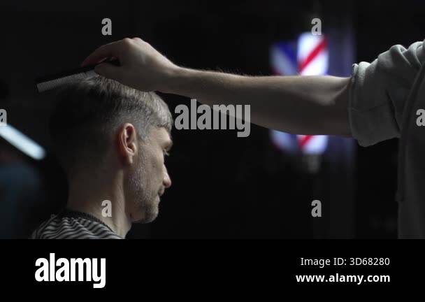 Barber examining customers hair and head shape before starting a ...