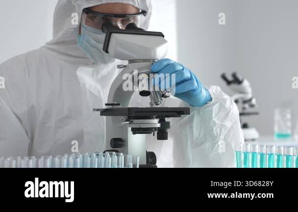 Medical virologist wearing a hazmat suit is working diligently with a ...