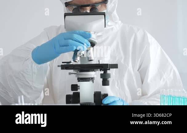 Medical virologist wearing a hazmat suit is working diligently with a ...