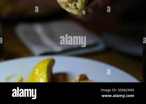 Hand uses fork to pick up calamari ring from seafood plate in bright ...