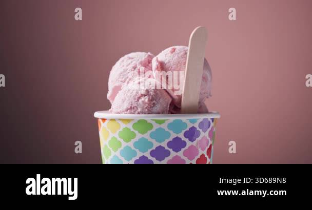 pink strawberry ice cream scoops in paper cup rotating, food closeup on ...