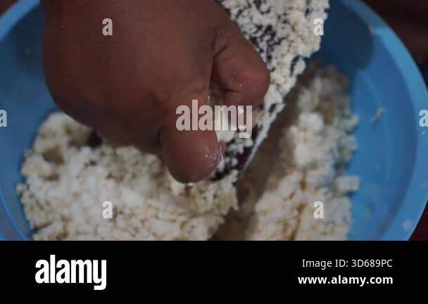 Close-up of a person manually grating cassava using a traditional ...
