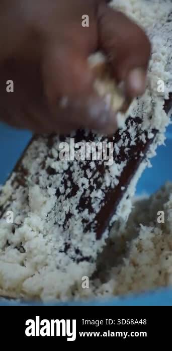 Close-up of a person manually grating cassava using a traditional ...