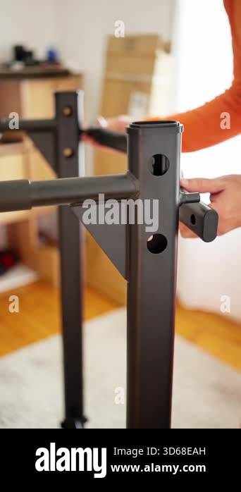 hands assemble metal bed frame latch in bright living room, orange ...