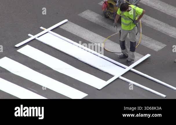 Applying road markings. Paint a pedestrian crossing with white color ...