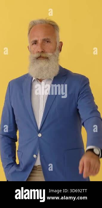 A serious senior man with a large white beard, wearing a blue jacket ...